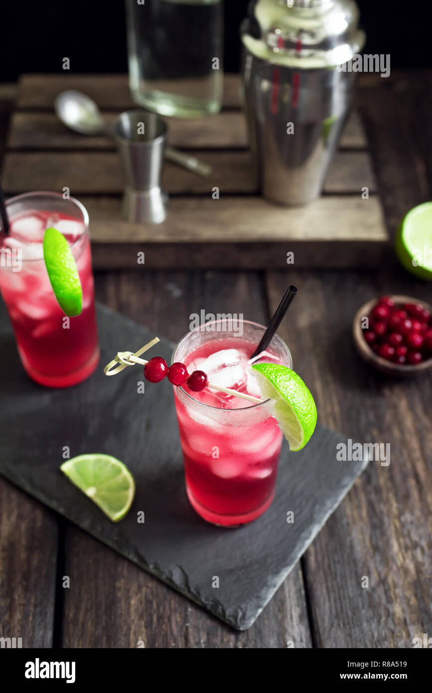 Cranberry Vodka Cocktail with lime and ice on black table. Cape Codder ...