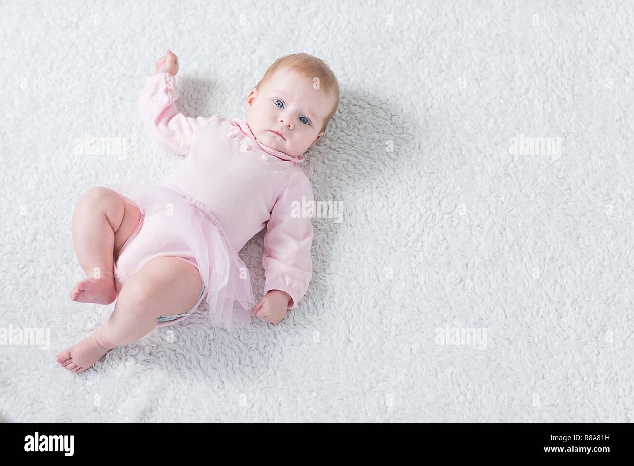 Tiny baby lies on his back on the floor and looking up Stock Photo - Alamy
