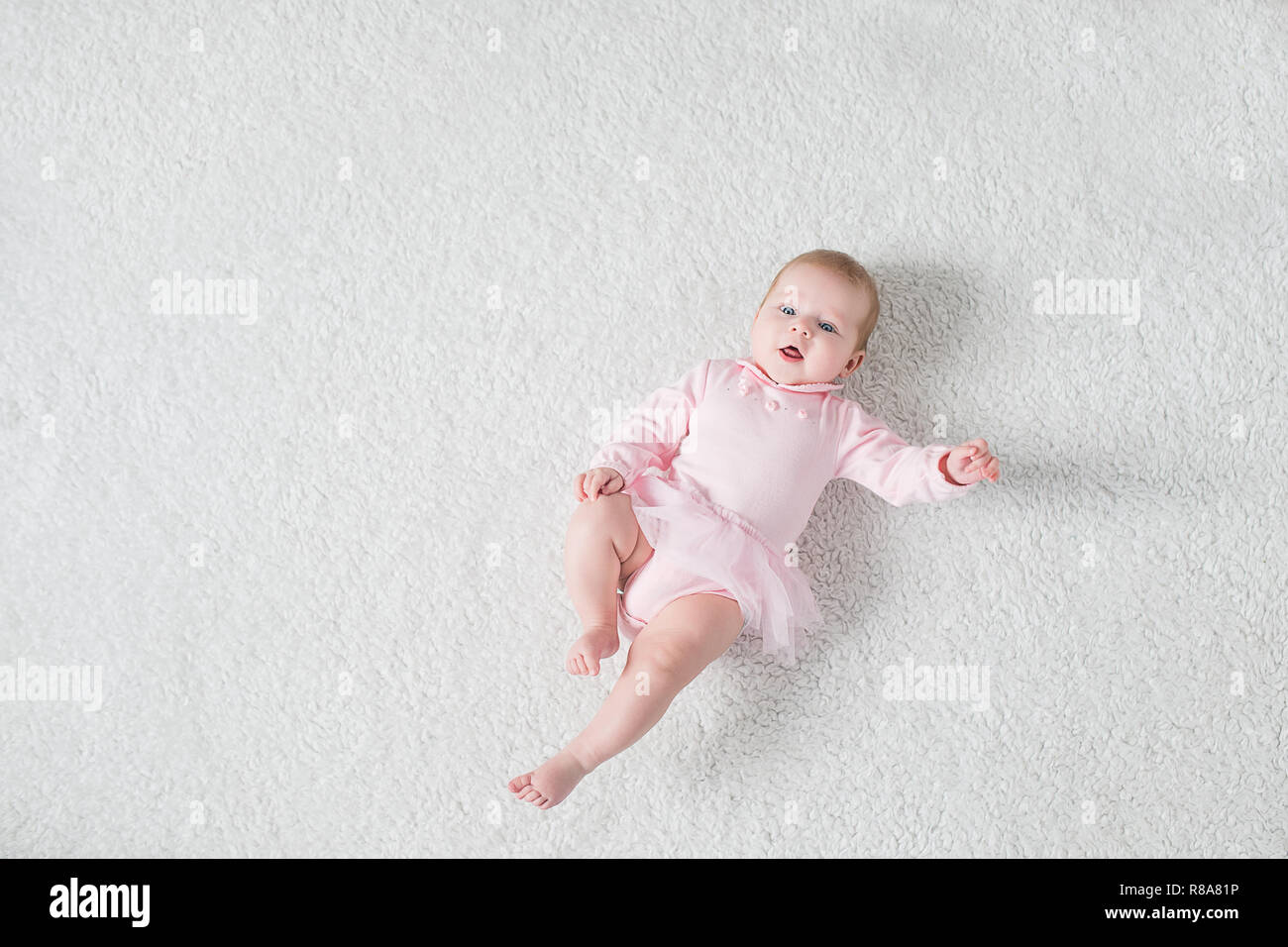 Tiny baby lies on his back on the floor and looking up Stock Photo - Alamy