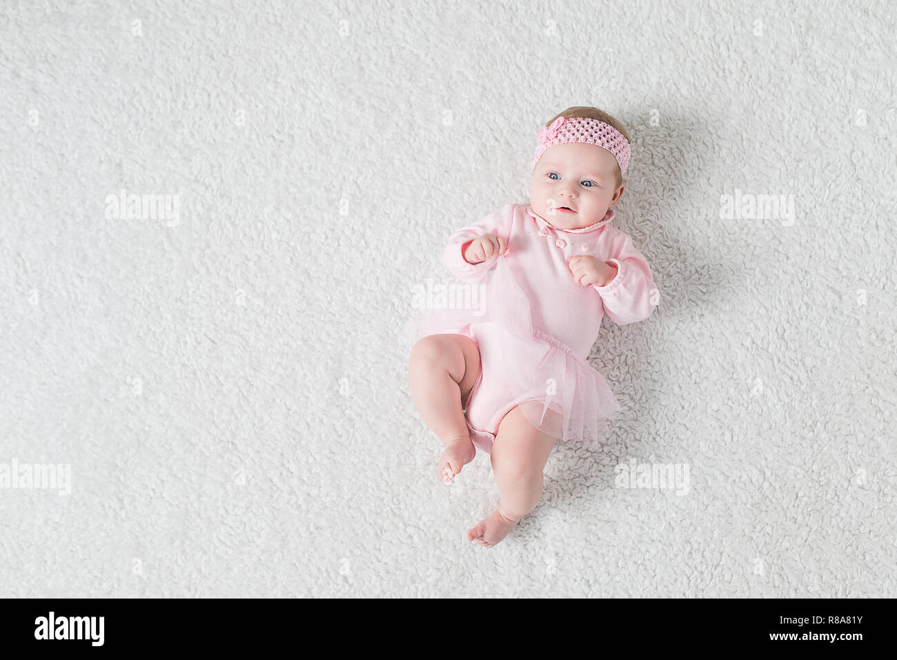 Tiny baby lies on his back on the floor and looking up Stock Photo - Alamy
