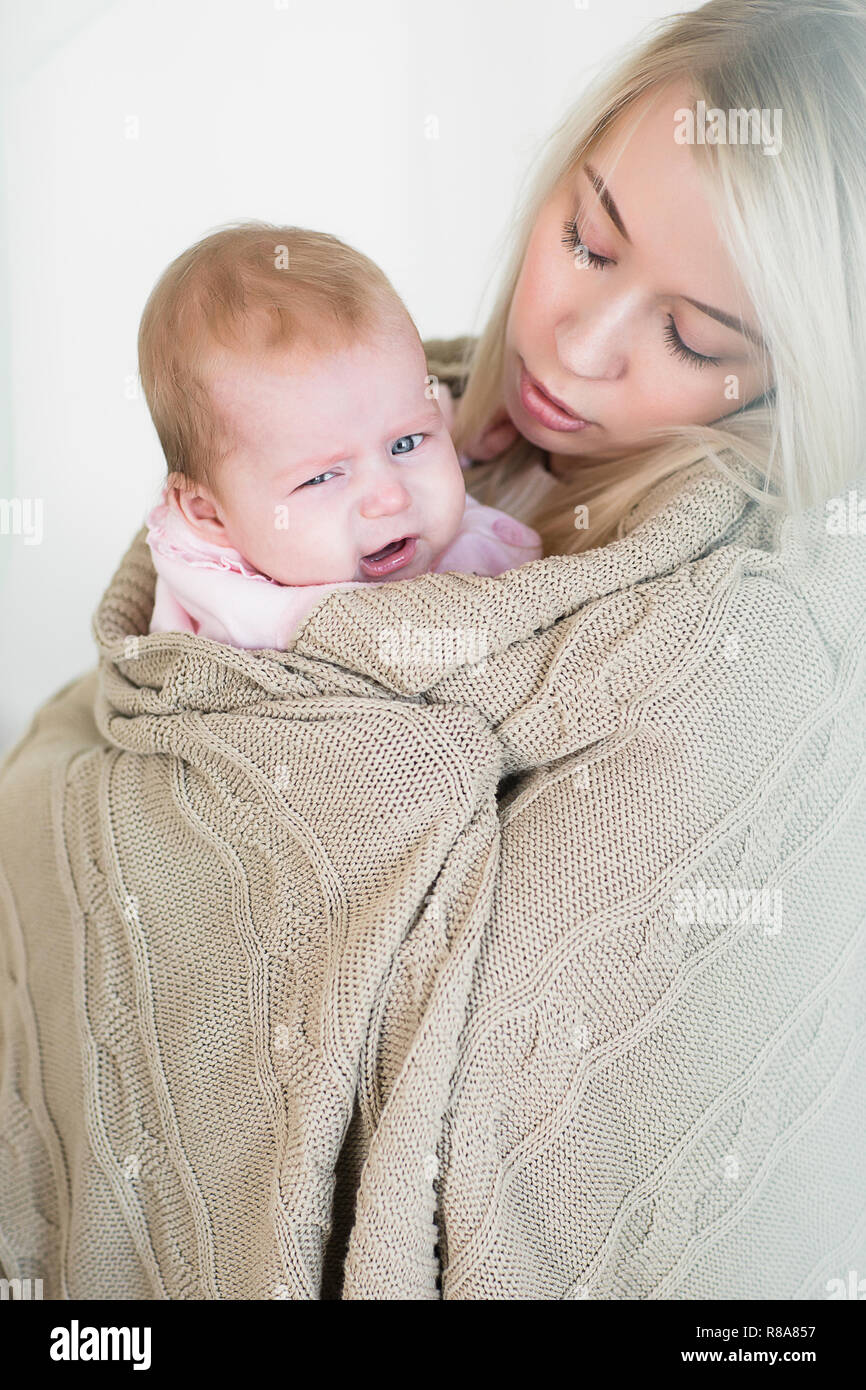 Young beautiful mother comforts, so as not to cry her infant daughter ...