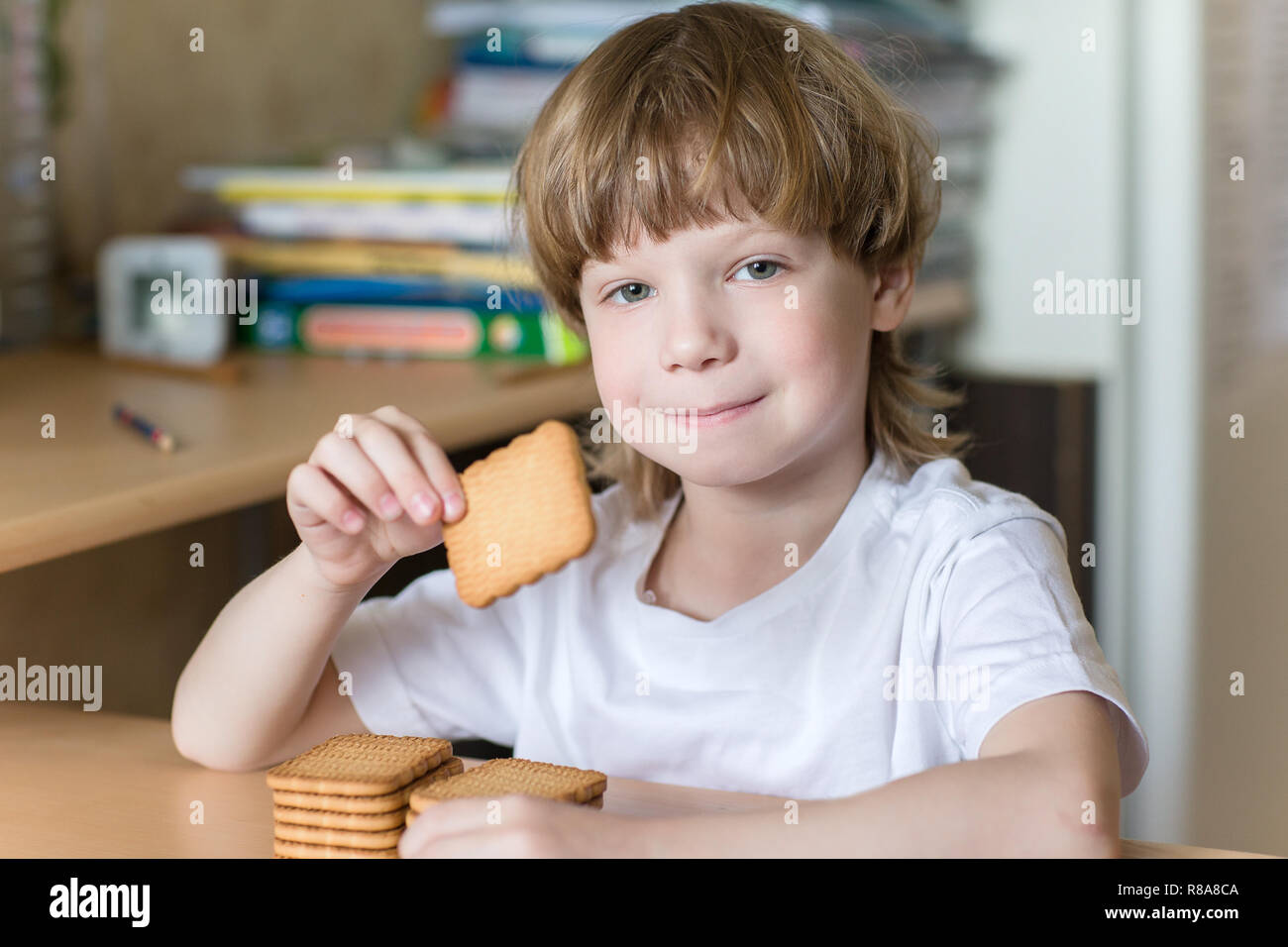child in the kitchen sitting at the table and eating cookies in the ...