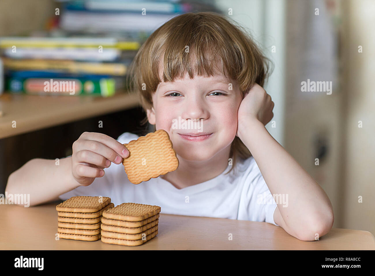 child in the kitchen sitting at the table and eating cookies in the ...