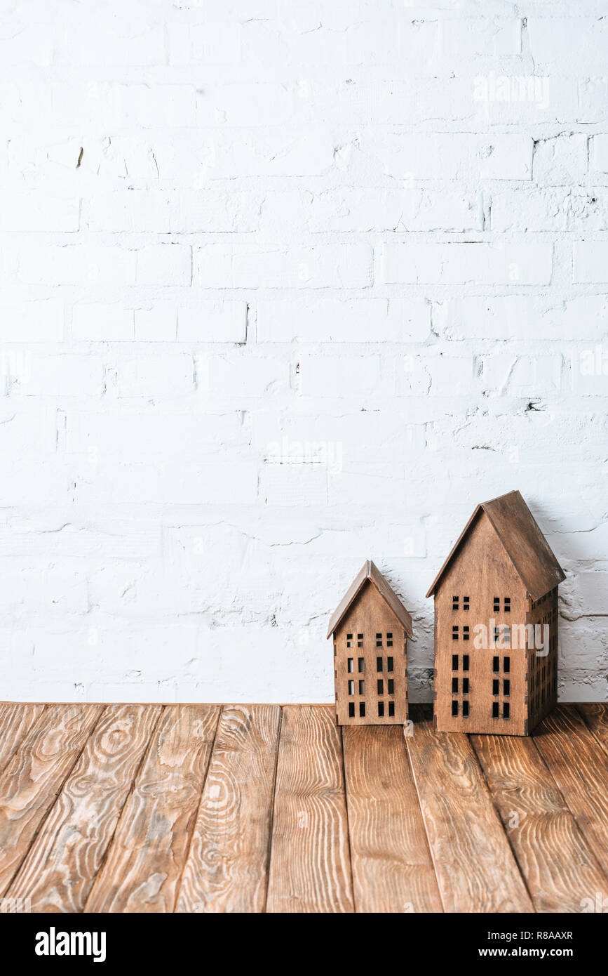 rustic house models on wooden table near white brick wall Stock Photo ...