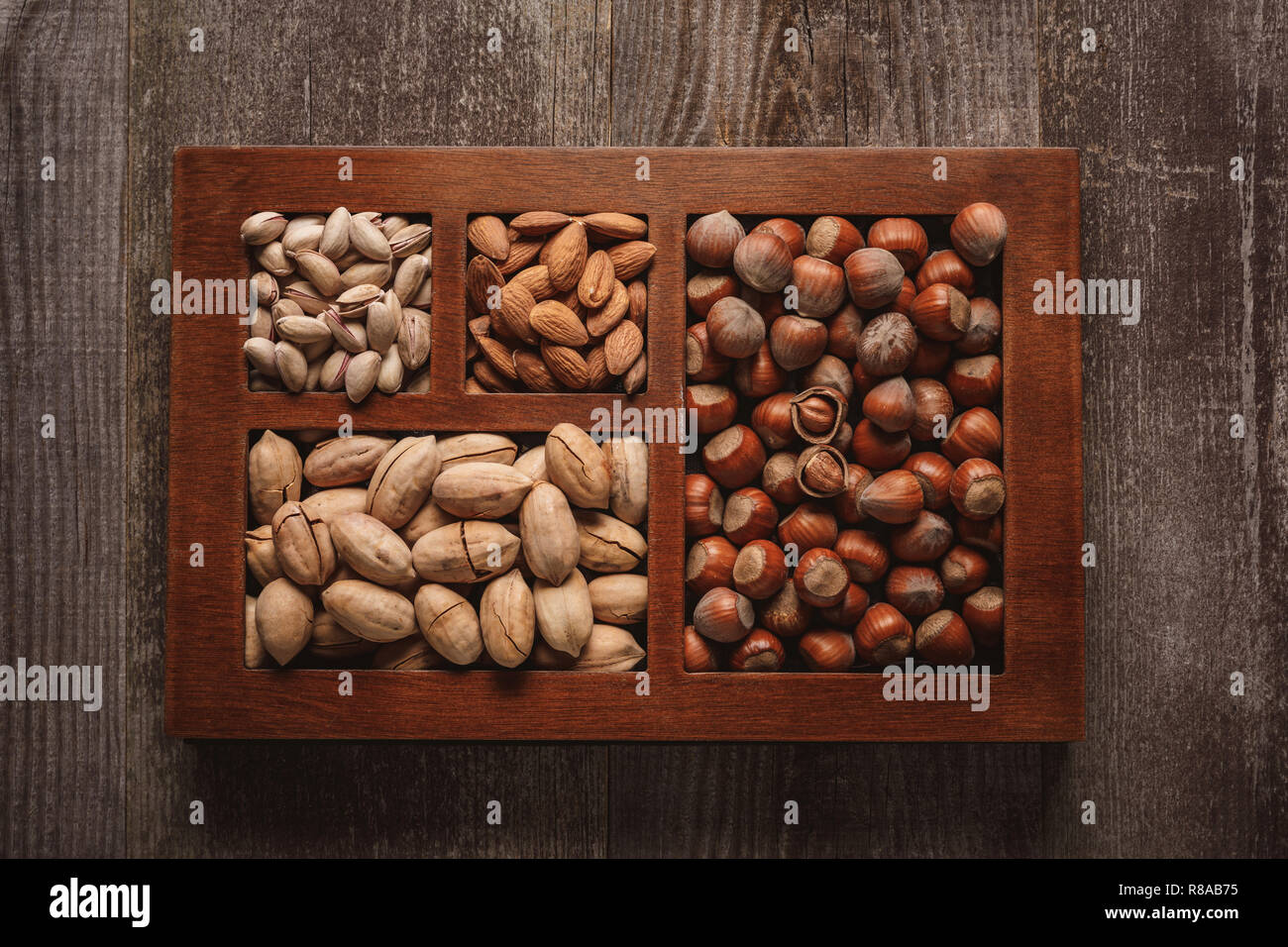 top view of assortment of various nuts in box on wooden background ...