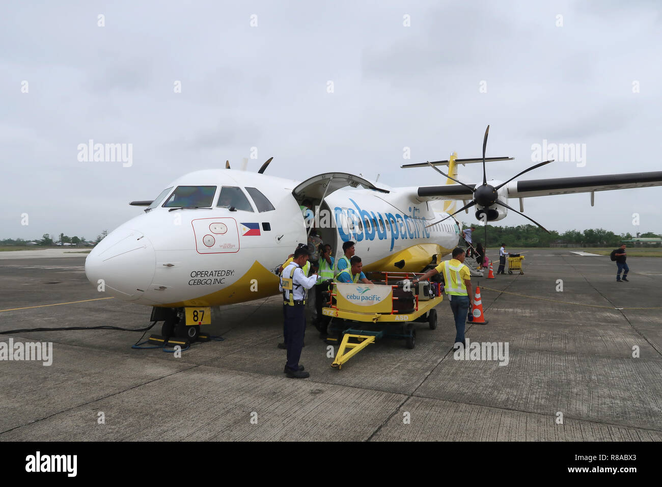 Baggage handlers unload luggage from a Cebu Pacific ATR 72-500 aircraft ...