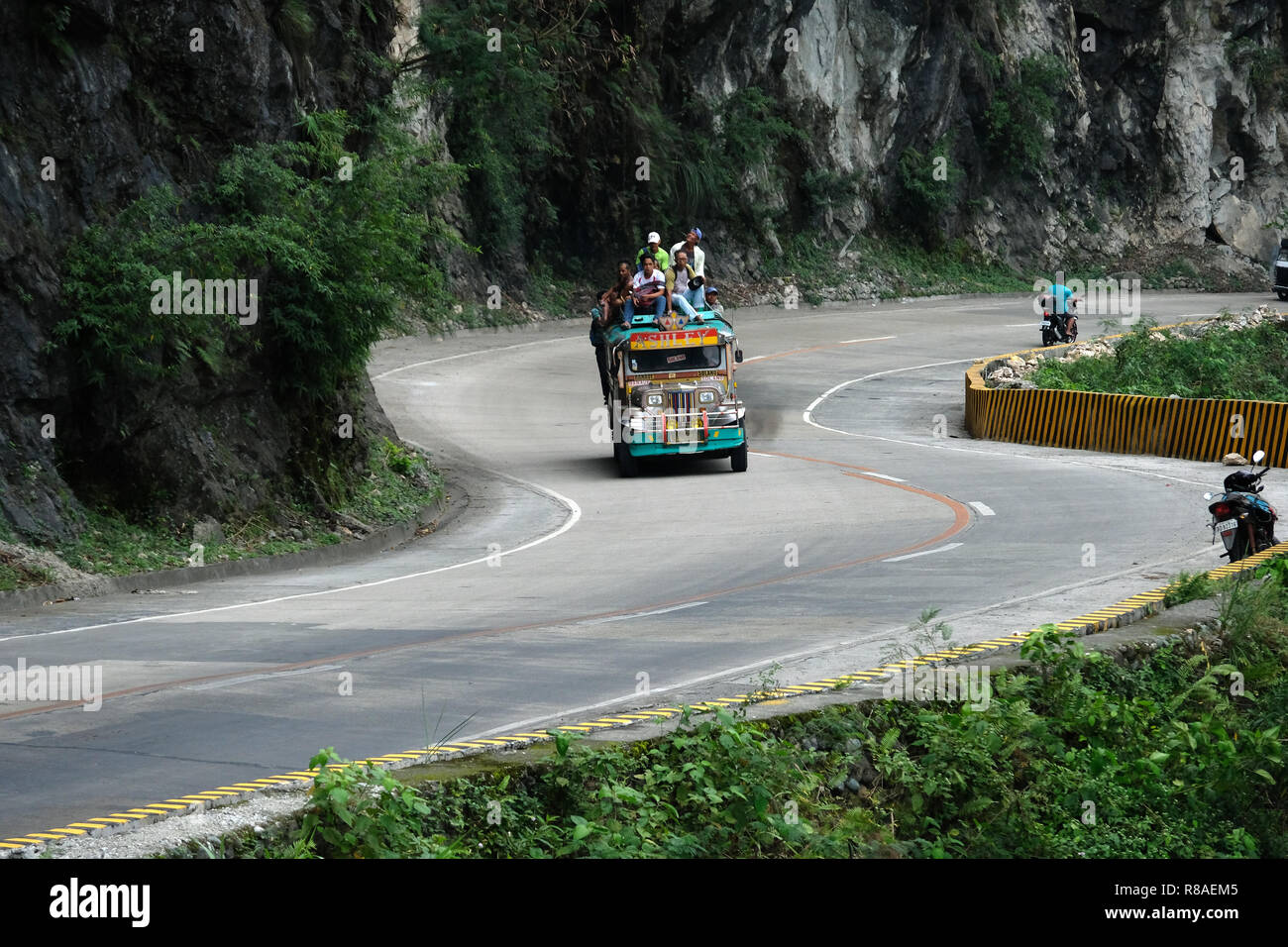 Fully packed Jeepney rides along a curved mountainous road in Isabela ...