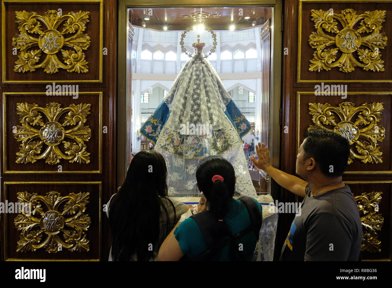 Filipino visitors praying in front of the 17th-century statue of the ...