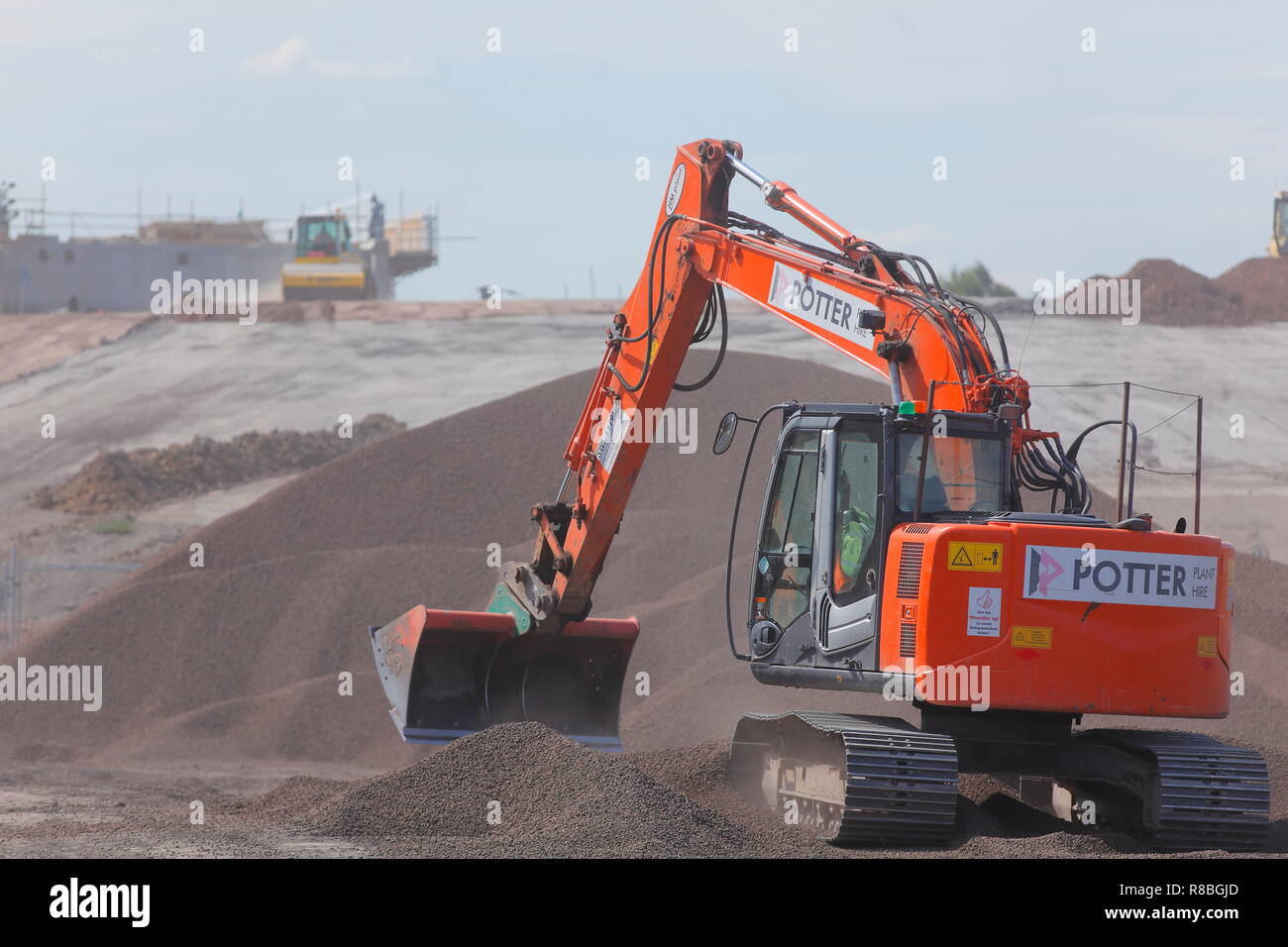 A Hitachi backhoe on a stockpile of lightweight aggregate fill which is ...