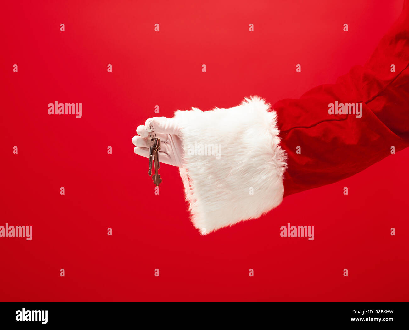 The hand of santa claus holding a apartment or car keys as gift on red ...