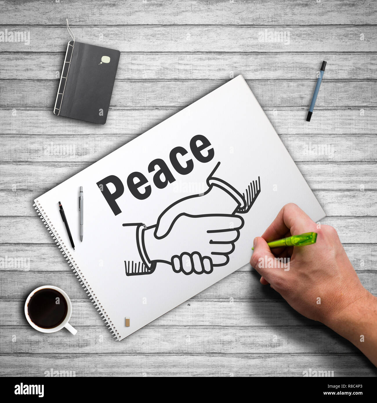 hand writing "peace" over a drawing of shaking hands on notepad on ...
