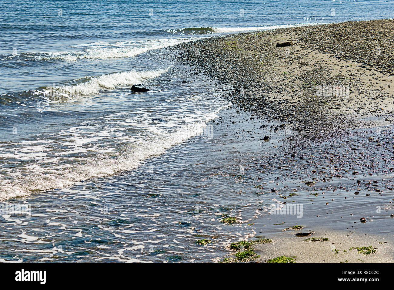 bright blue ocean waves flowing over a gravel shore Stock Photo - Alamy