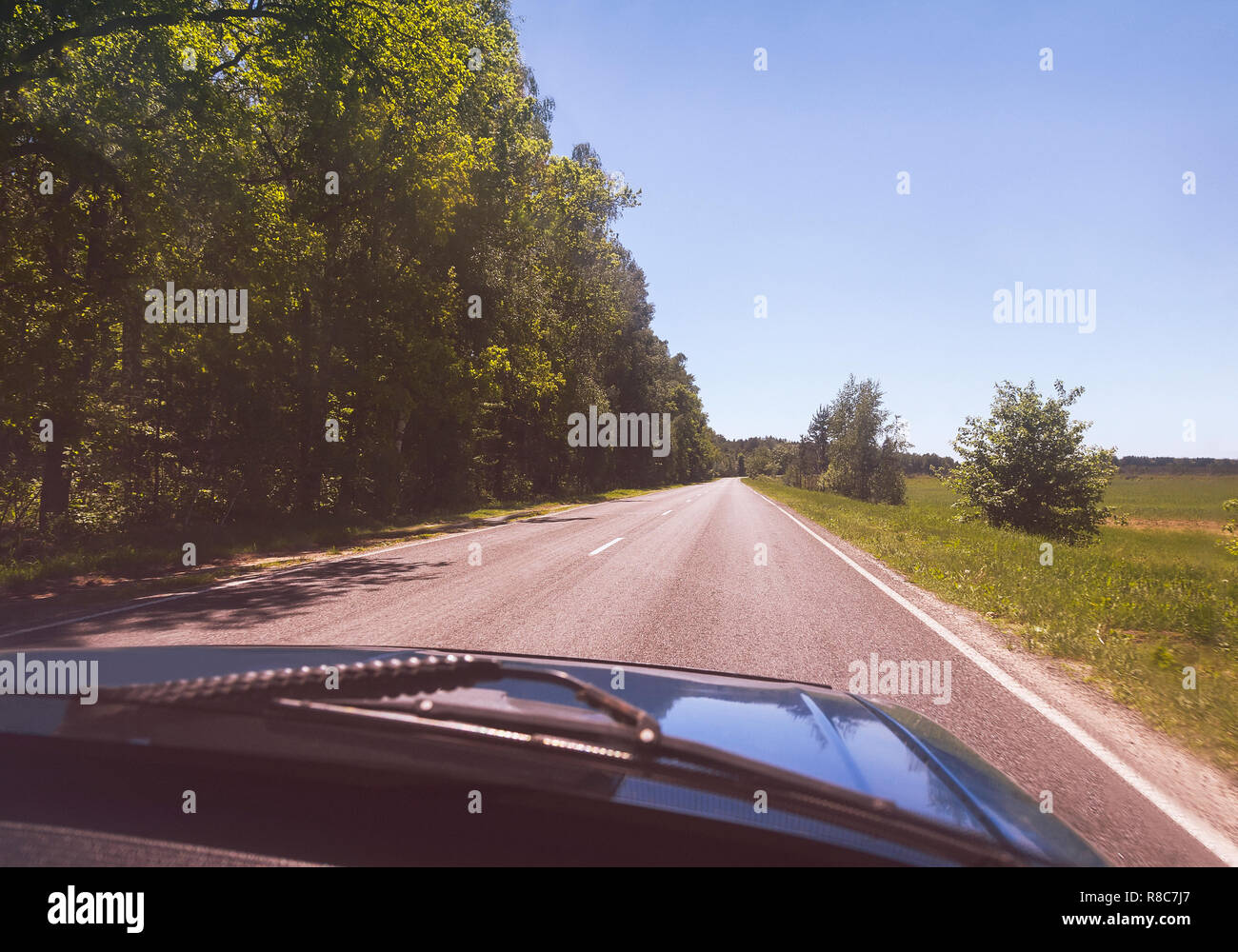 From the front window of the car is visible asphalt road along the ...