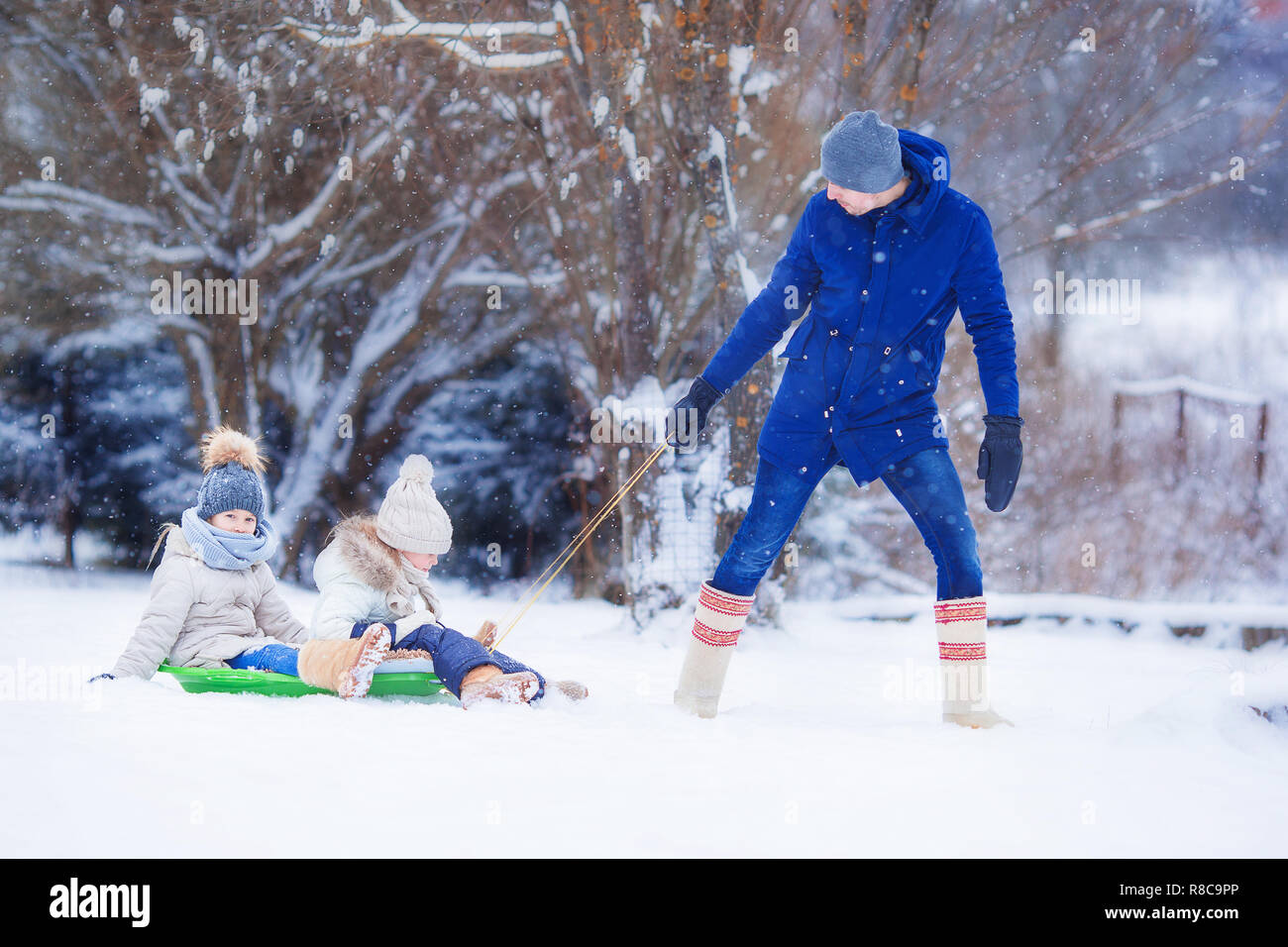 Little girls enjoy a sleigh ride. Father sledding his little adorable ...
