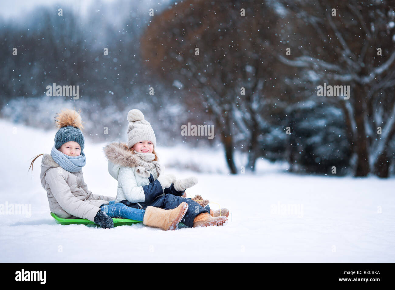 Little adorable girls enjoy a sleigh ride. Child sledding. Children ...