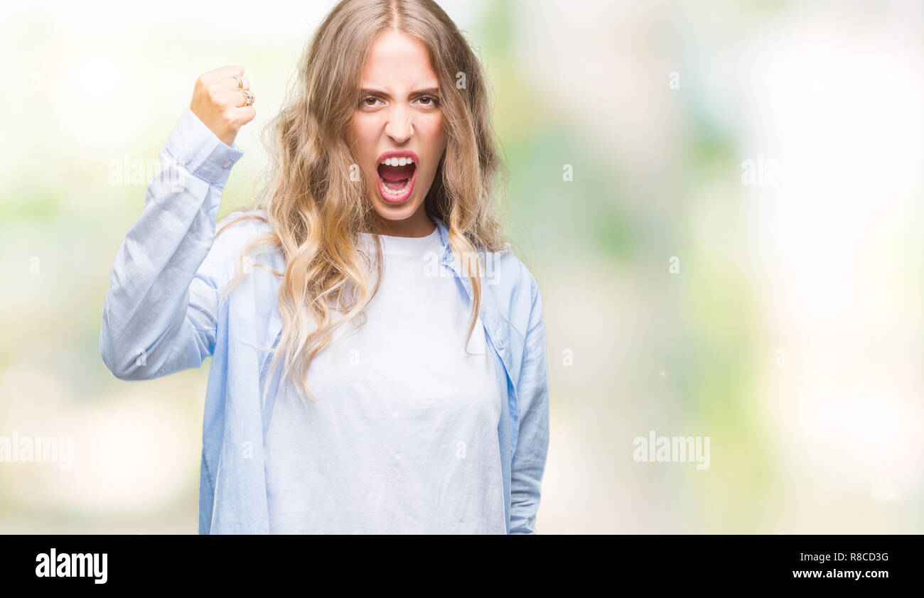 Beautiful young blonde woman over isolated background angry and mad ...