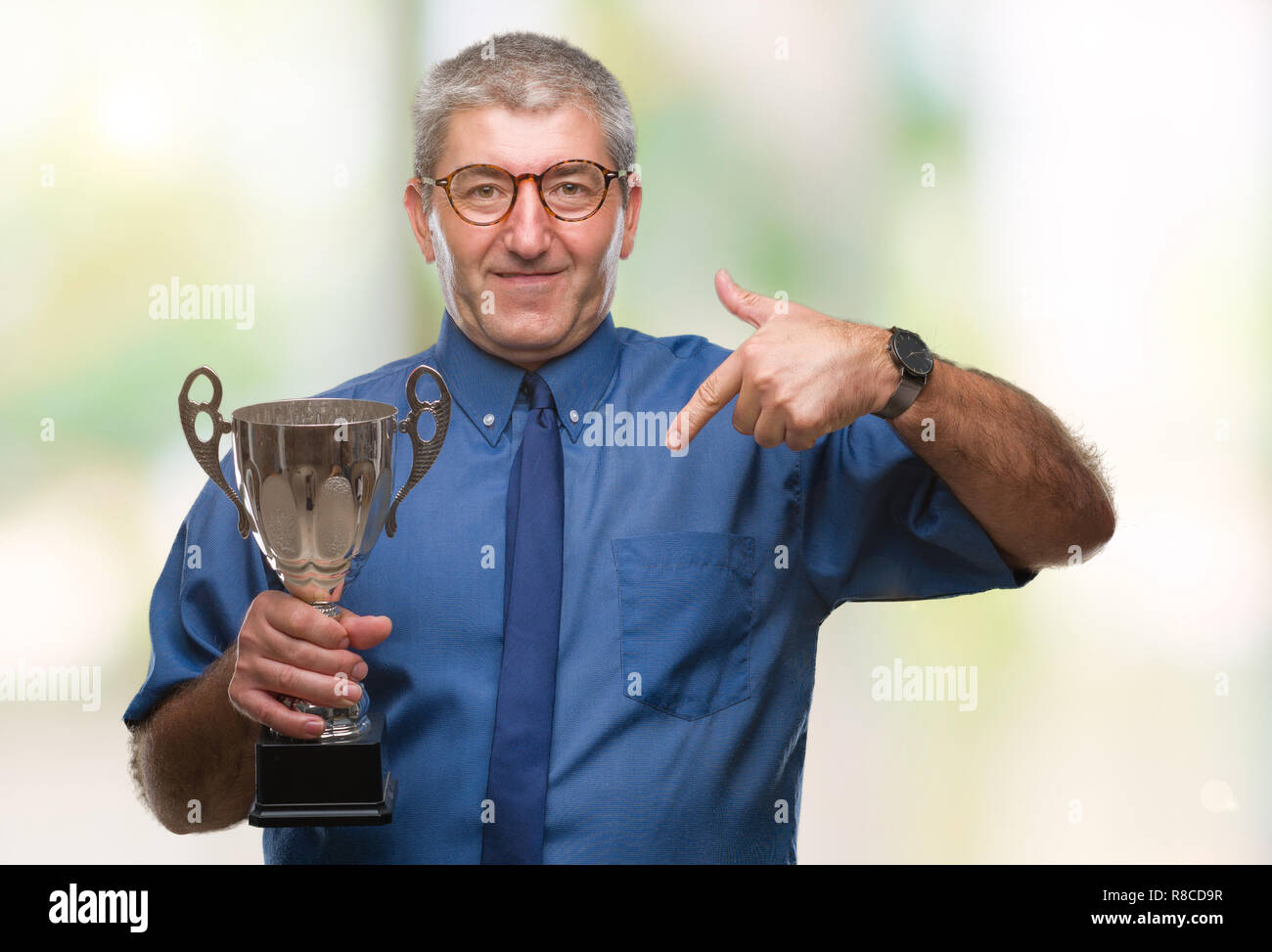 Handsome senior successful man holding trophy over isolated background ...