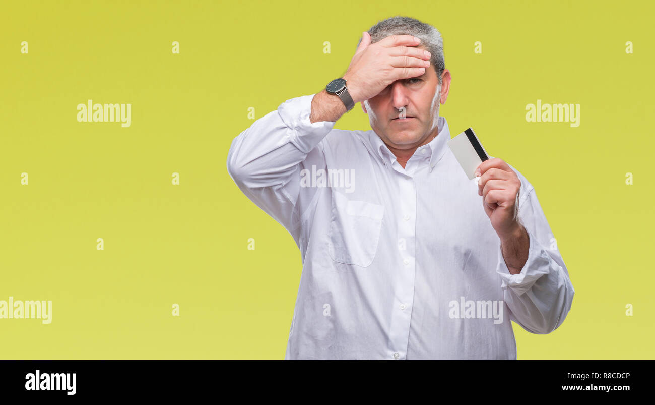 Handsome senior man holding credit card over isolated background ...