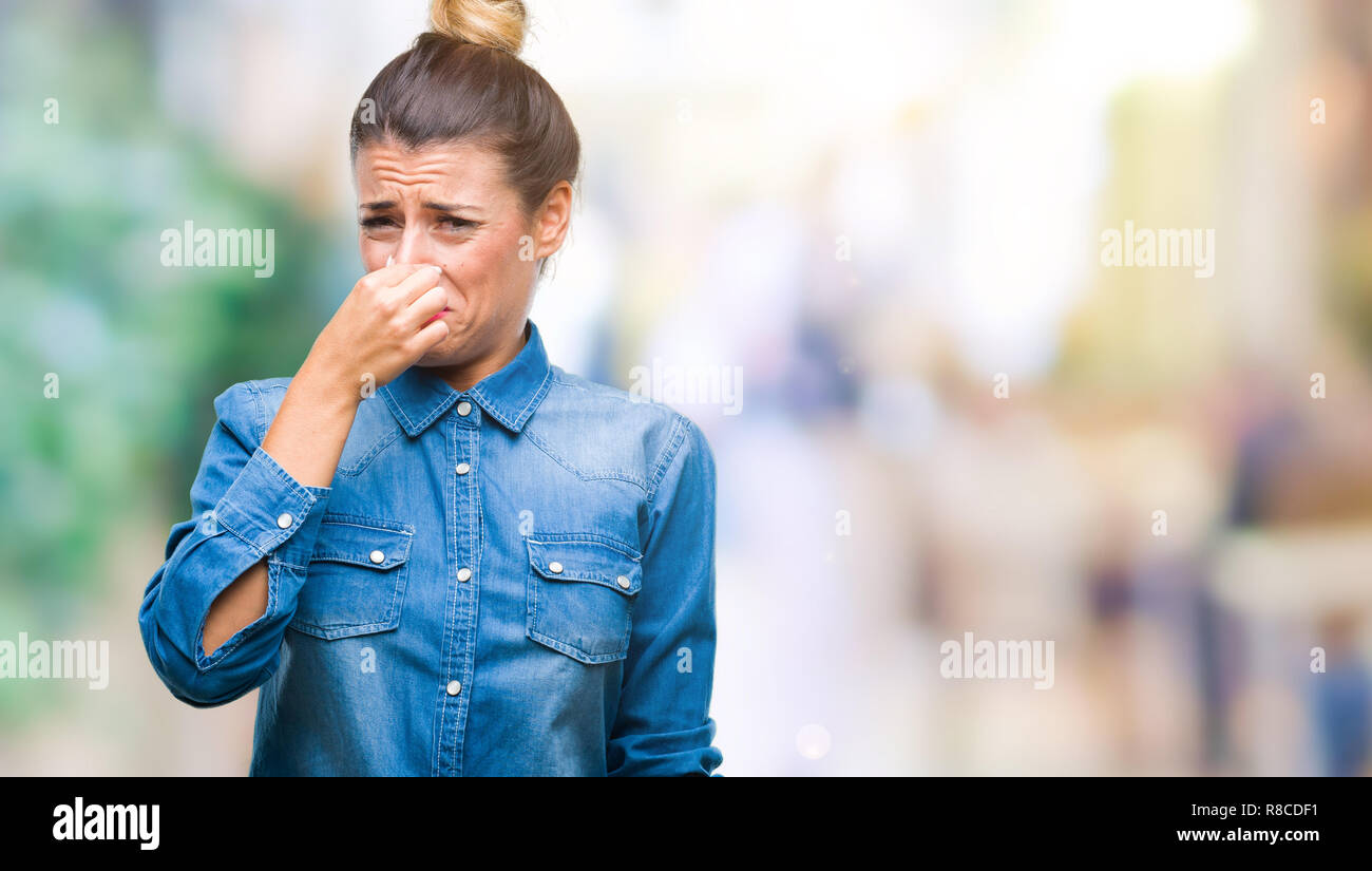 Young beautiful woman over isolated background smelling something ...