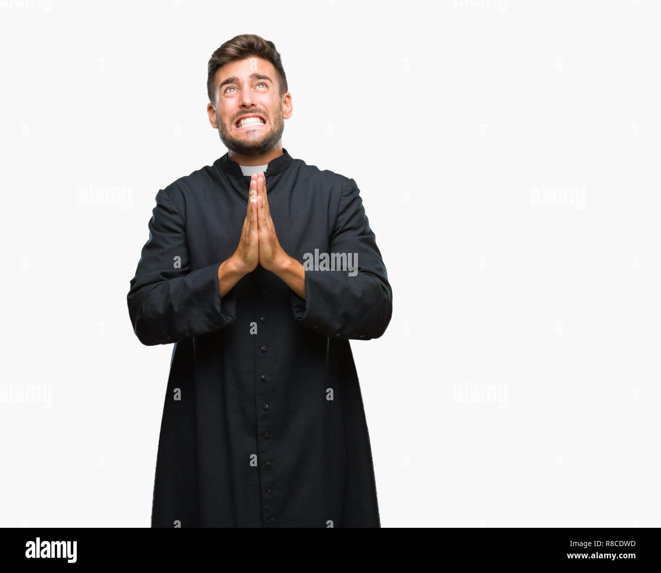 Young catholic christian priest man over isolated background begging ...