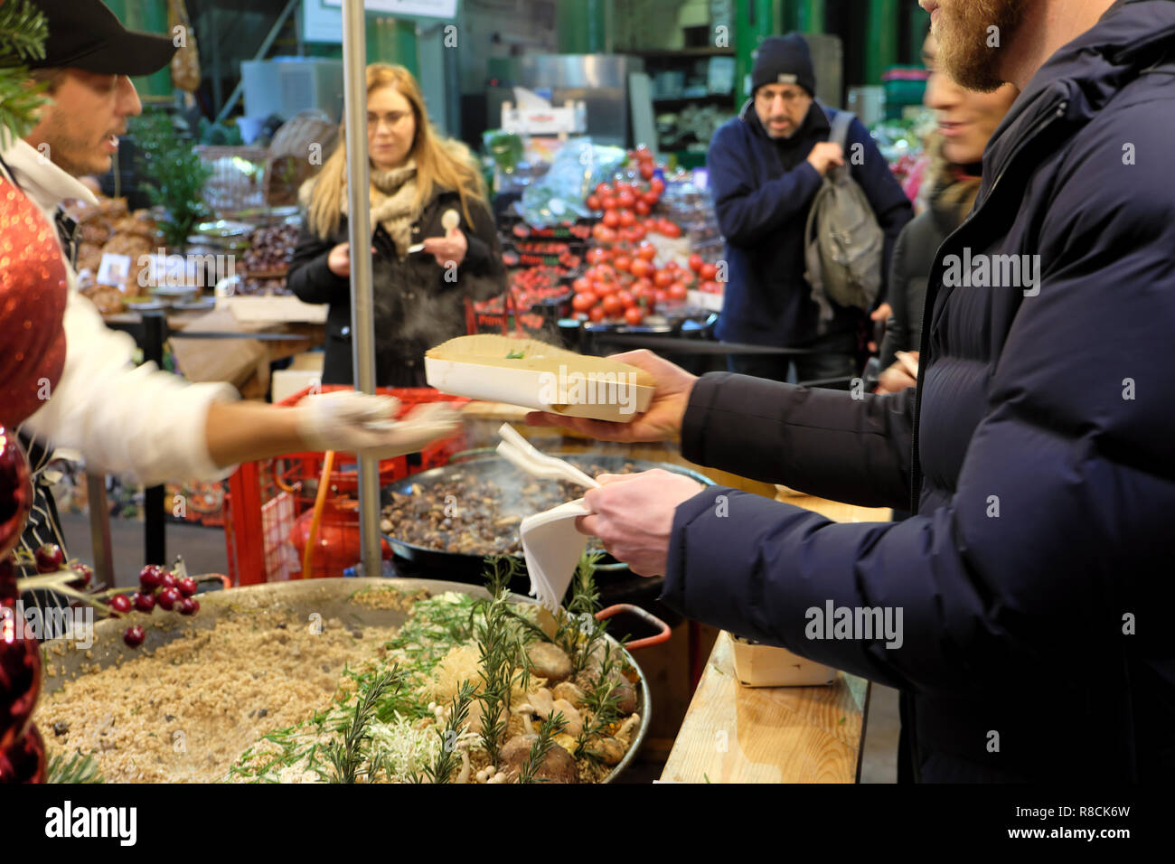 An Italian chef handing a customer a food carton with hot wild mushroom ...