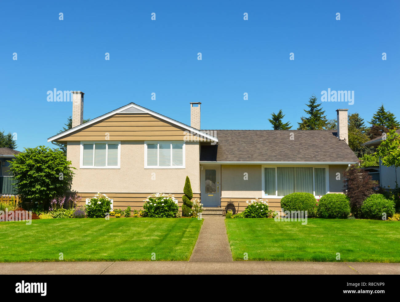 Average family house with green lawn and trees in front on blue sky ...