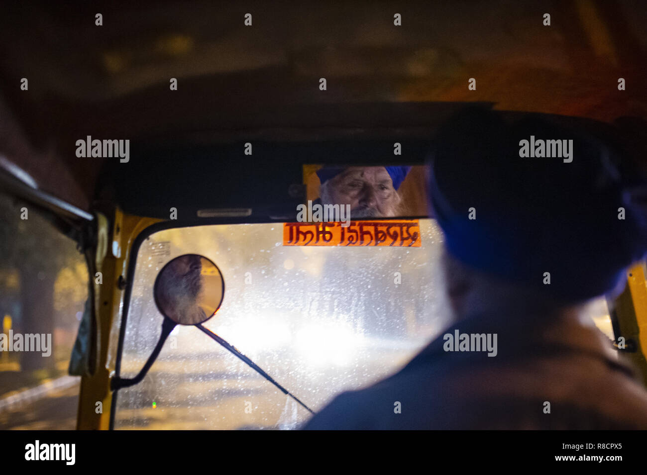 An auto-rickshaw driver is driving in the streets of New Delhi at night ...