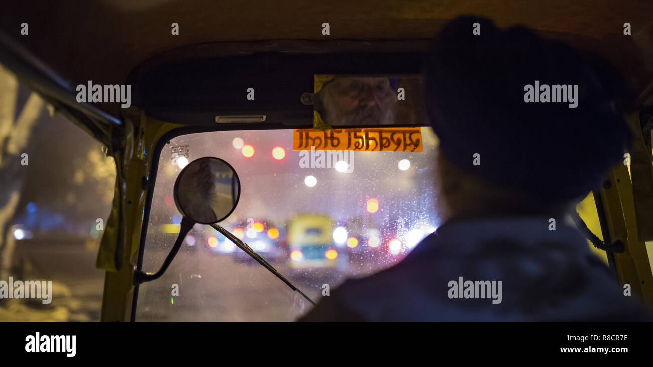 An auto-rickshaw driver is driving in the streets of New Delhi at night ...