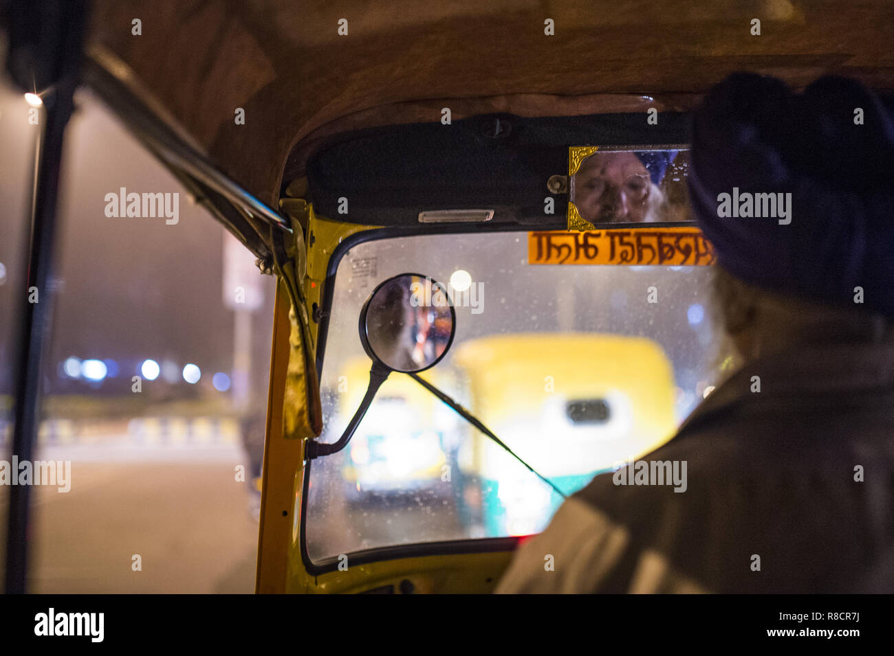 An auto-rickshaw driver is driving in the streets of New Delhi at night ...