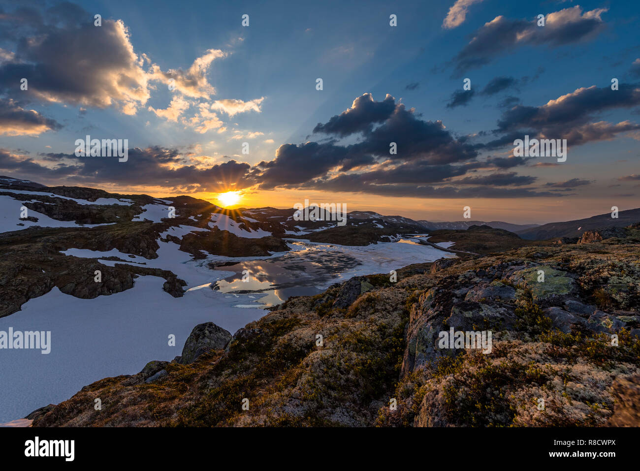 The spring sunset setting the mountain landscape with a melting lake in ...