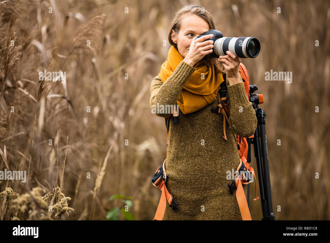 Pretty, female photographer taking pictures outdoor on a lovely autumn ...