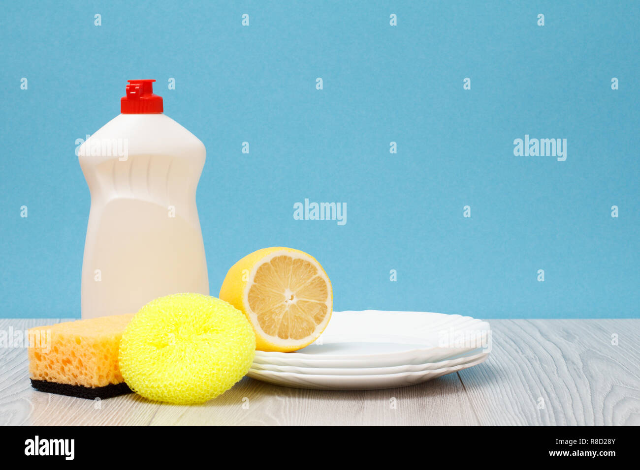 Plastic bottle of dishwashing liquid, sponges, clean plates and lemon ...