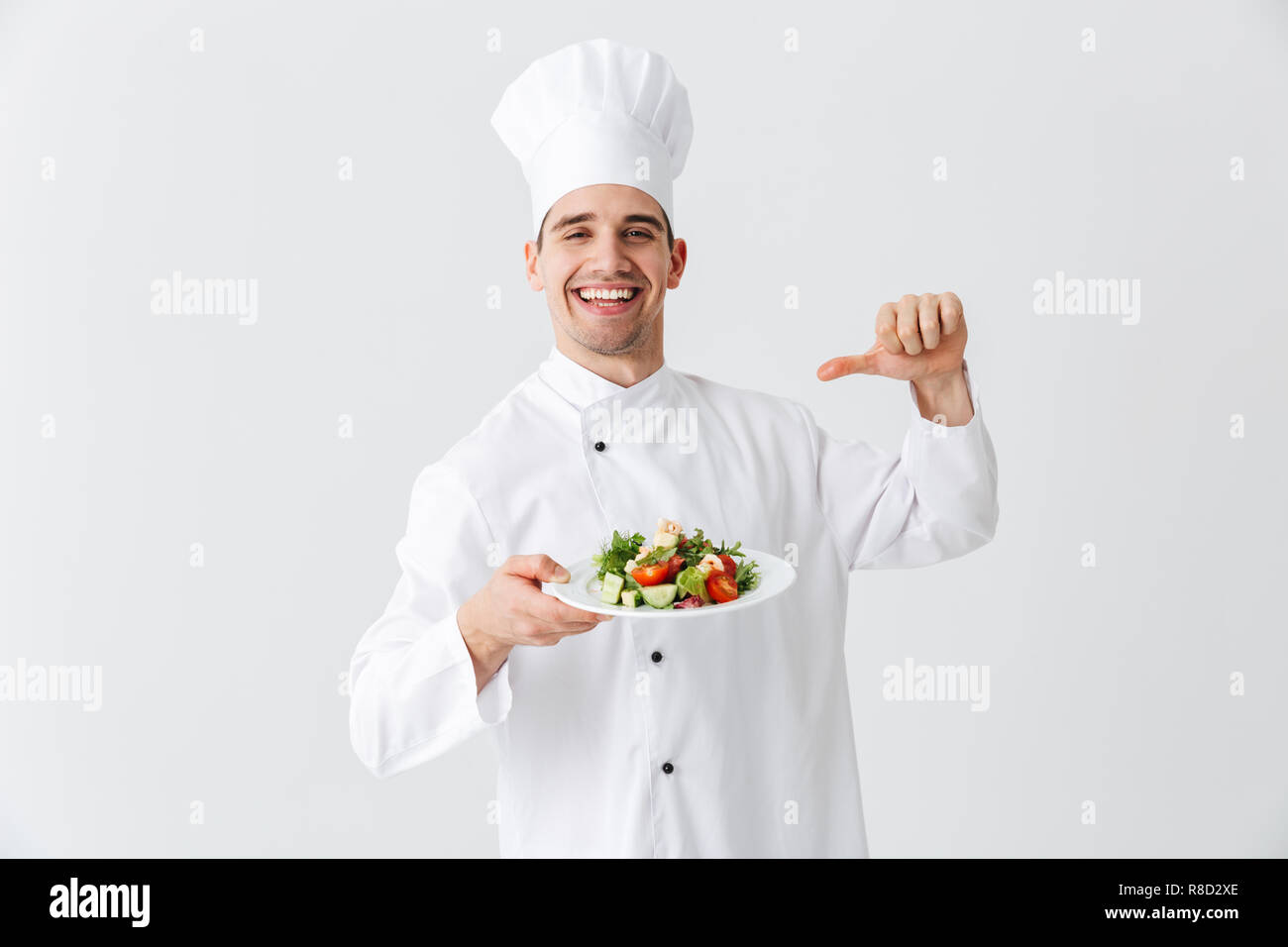 Excited man chef cook wearing uniform showing fresh green salad on a ...