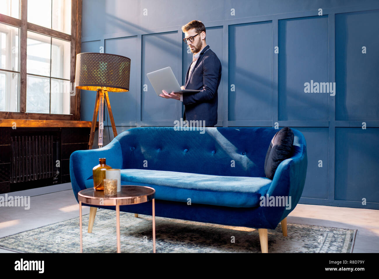 Portrait of an elegant businessman sitting with laptop on the couch at ...
