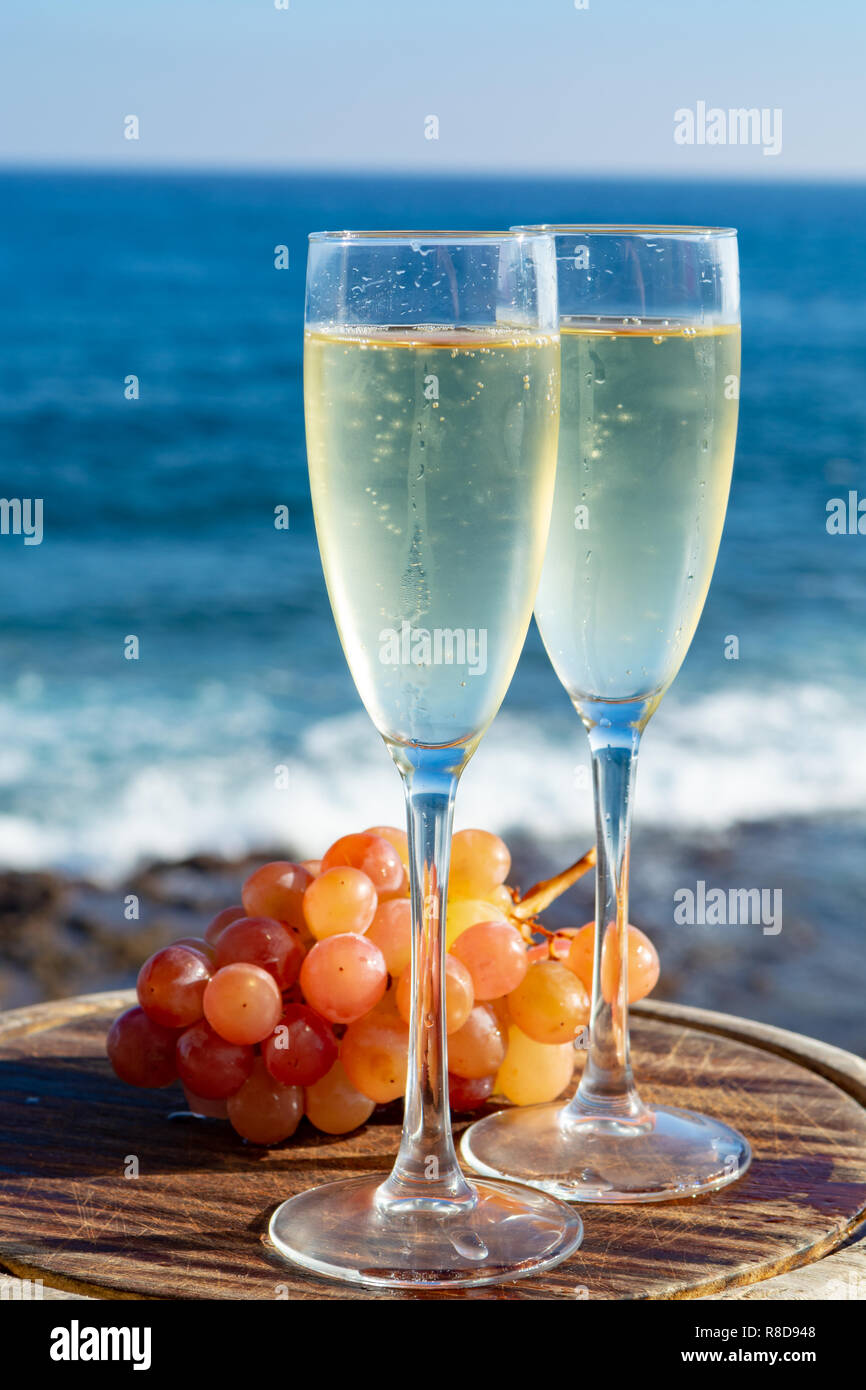 Champagne, prosecco or cava served with pink grape in two glasses on ...