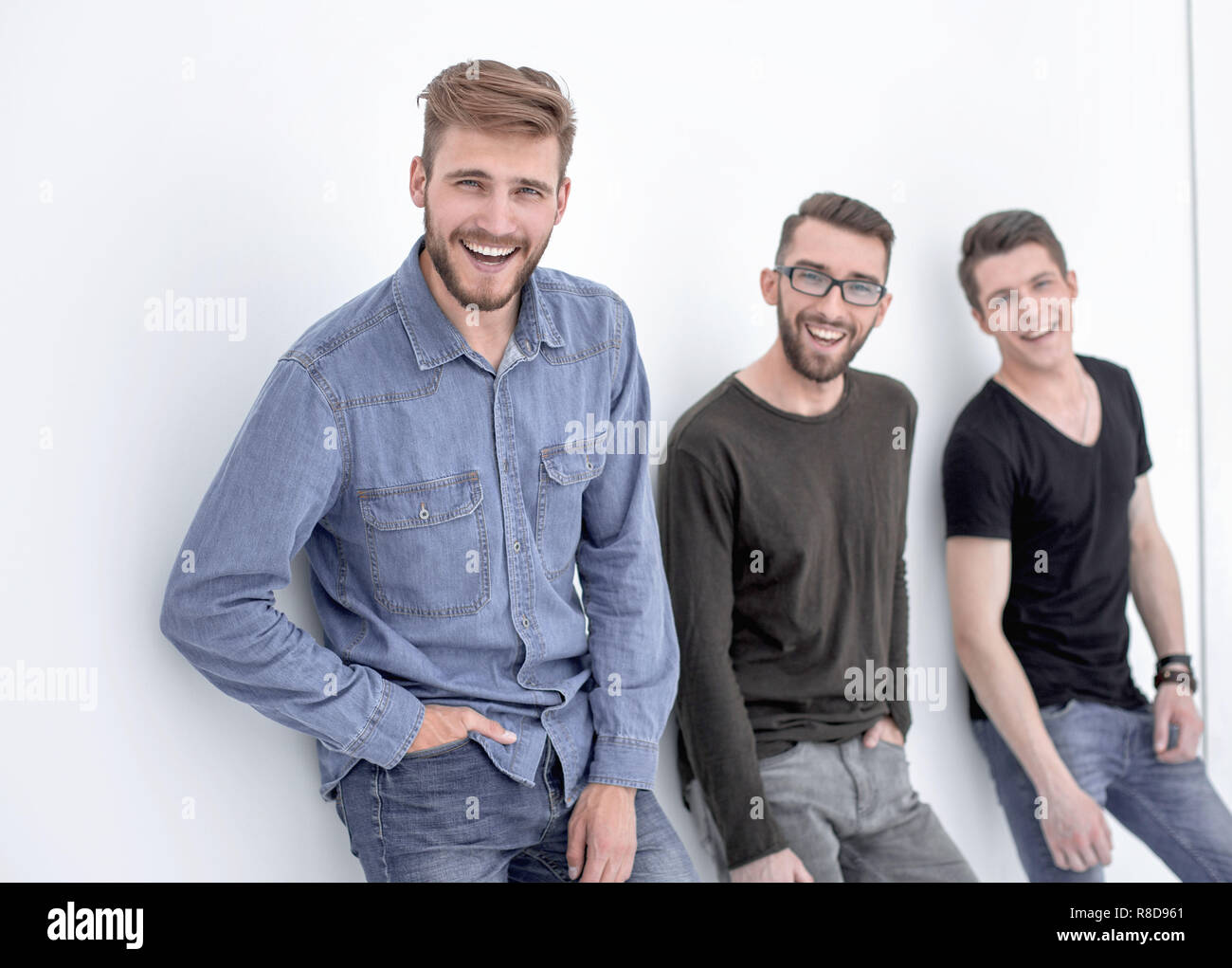 three people leaning against the wall, smiling Stock Photo - Alamy