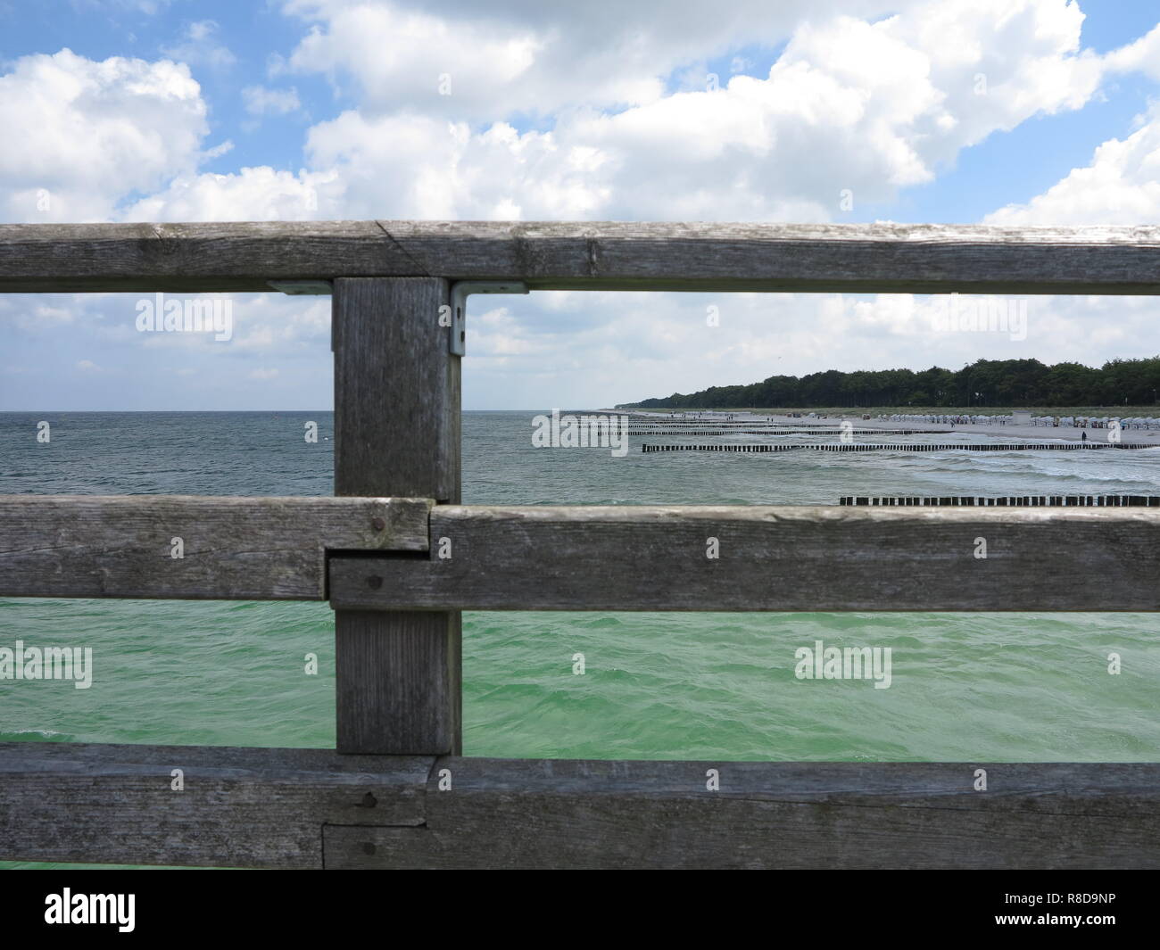 View through a wooden railing on a beach and a sky with clouds in ...