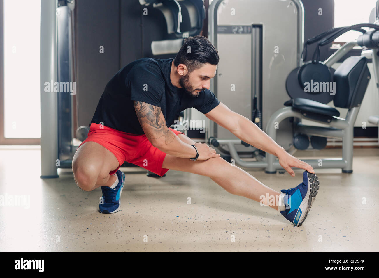 Strong bearded man in the gym stretching Stock Photo - Alamy