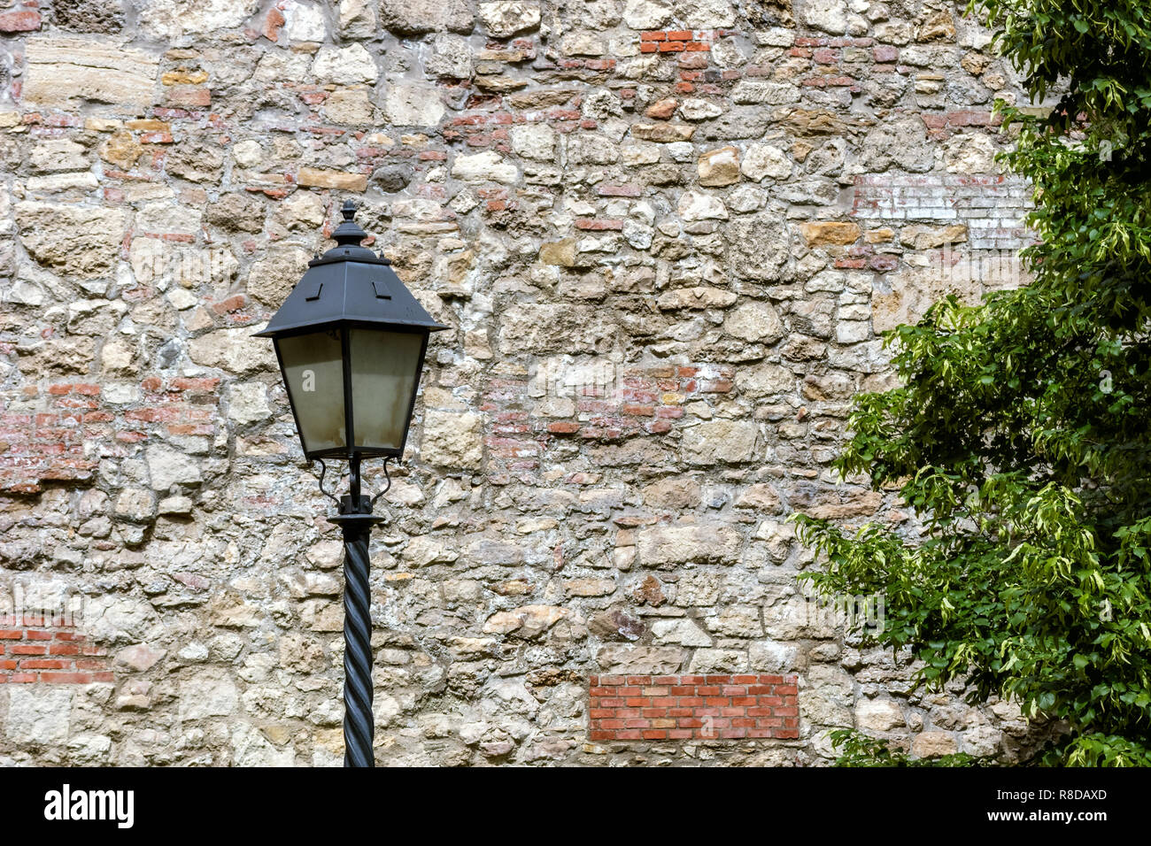 Street lamp on the background of an old stone wall interspersed with ...