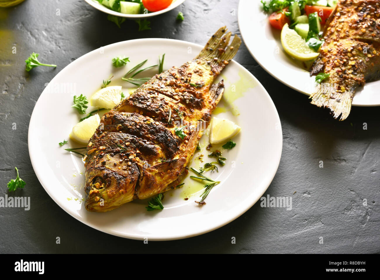Fried fish on plate over black stone table Stock Photo - Alamy