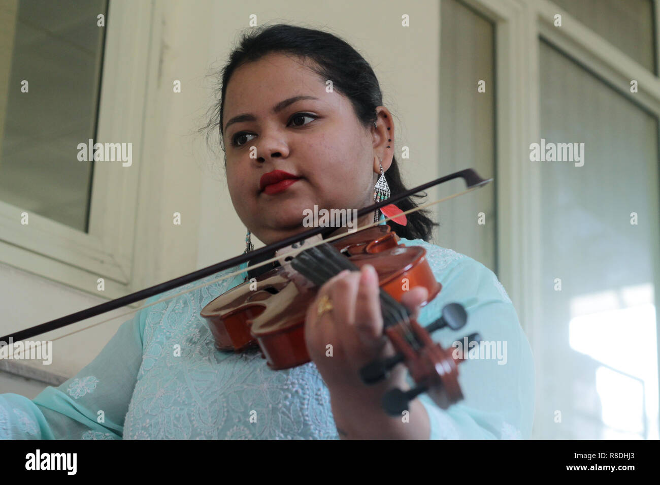 A young beautiful woman playing a wooden stringed musical instrument ...