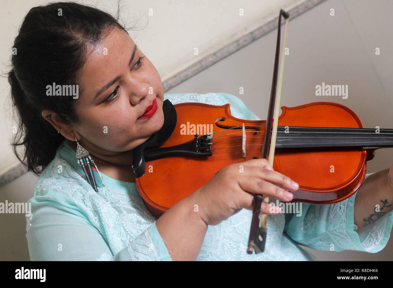 A young beautiful woman playing a wooden stringed musical instrument ...