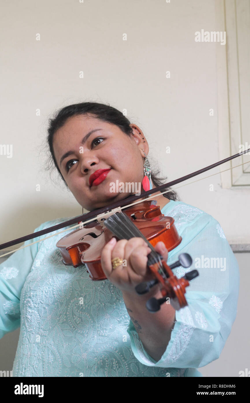 A young beautiful woman playing a wooden stringed musical instrument ...