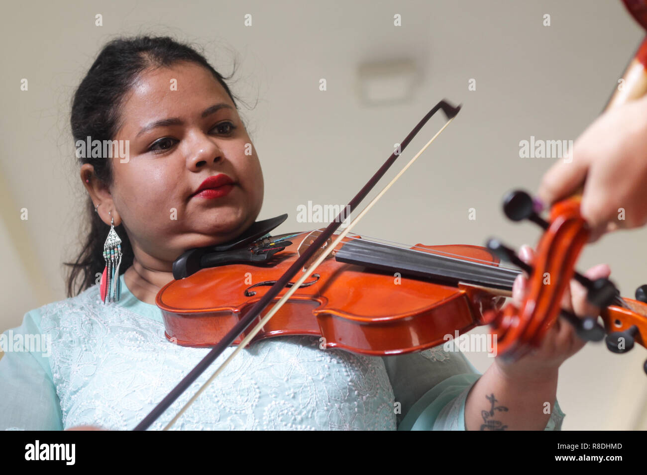 A young beautiful woman playing a wooden stringed musical instrument ...