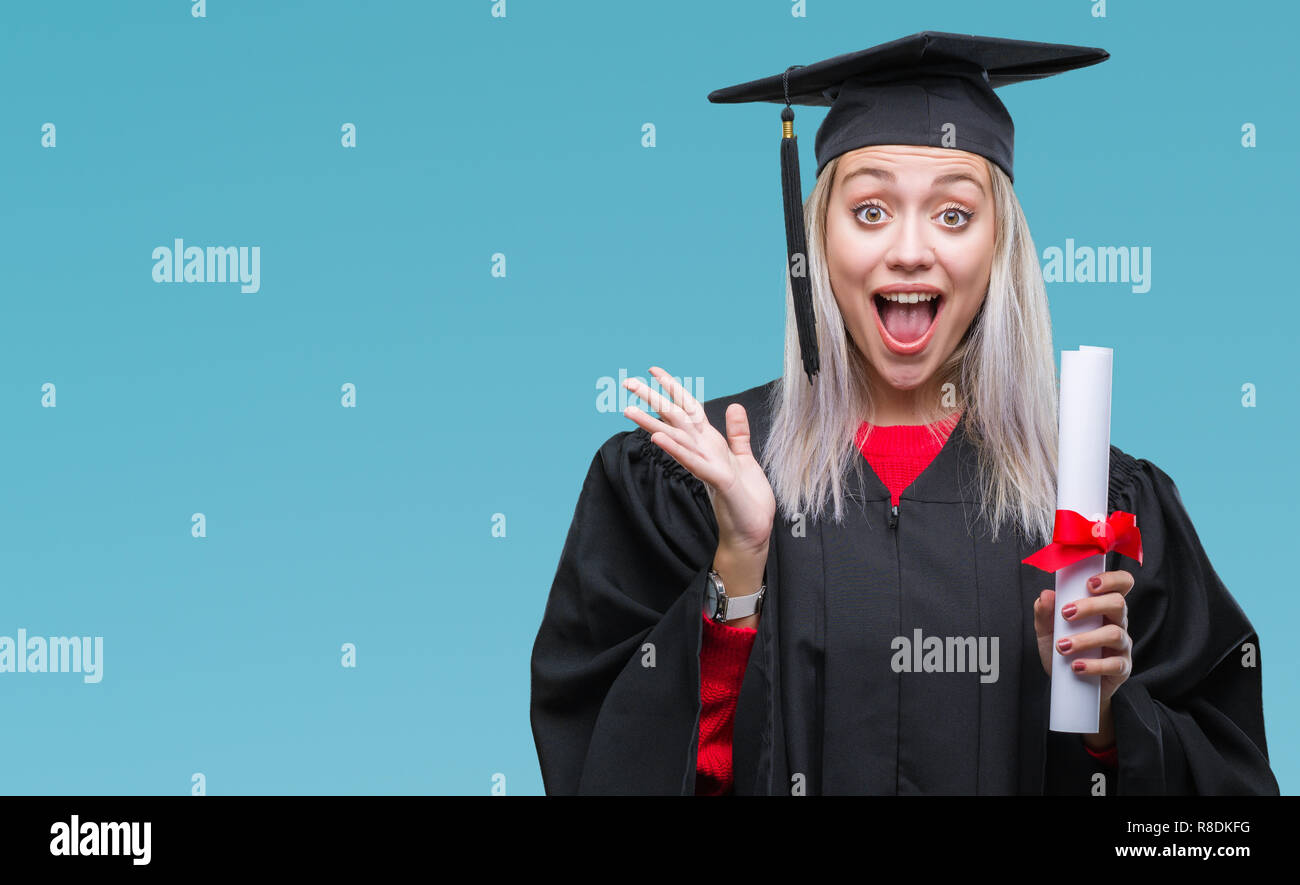 Young blonde woman wearing graduate uniform holding degree over ...
