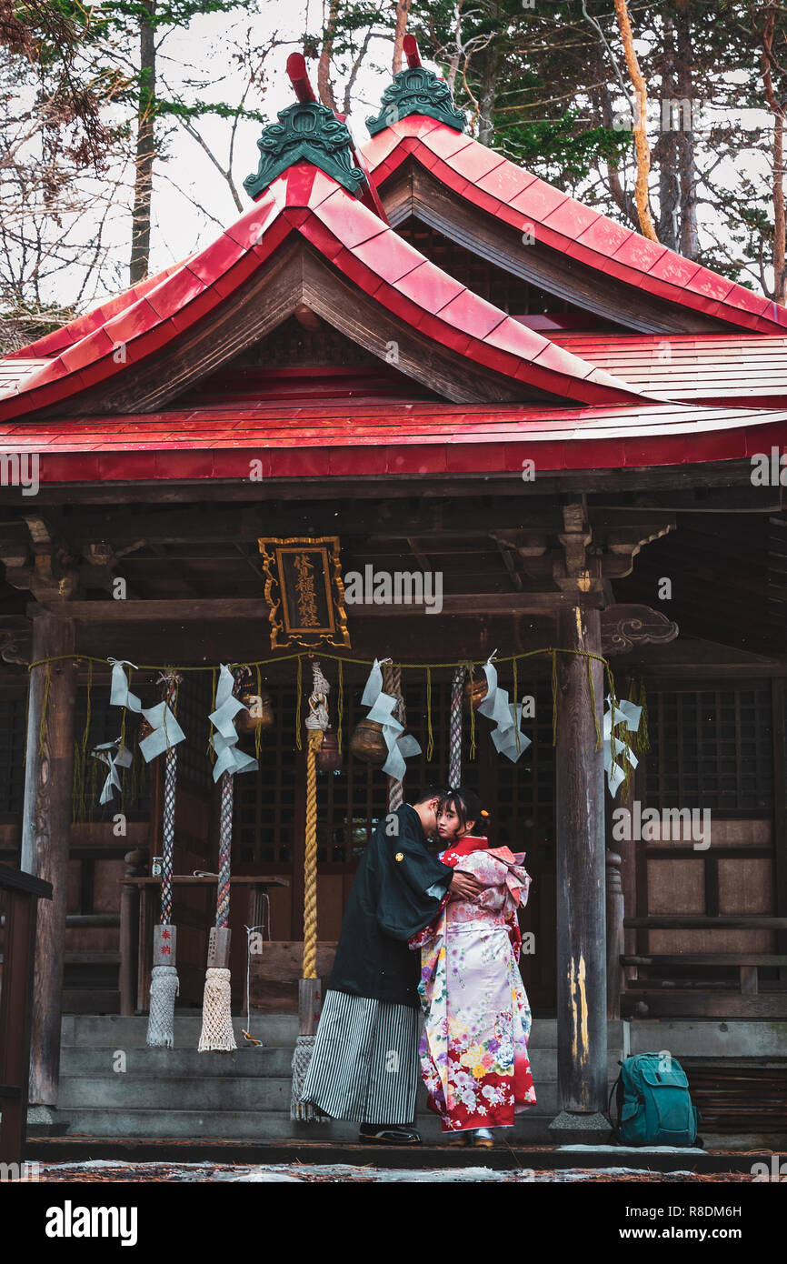 A young newly married japanese couple in traditional dresses paying a ...