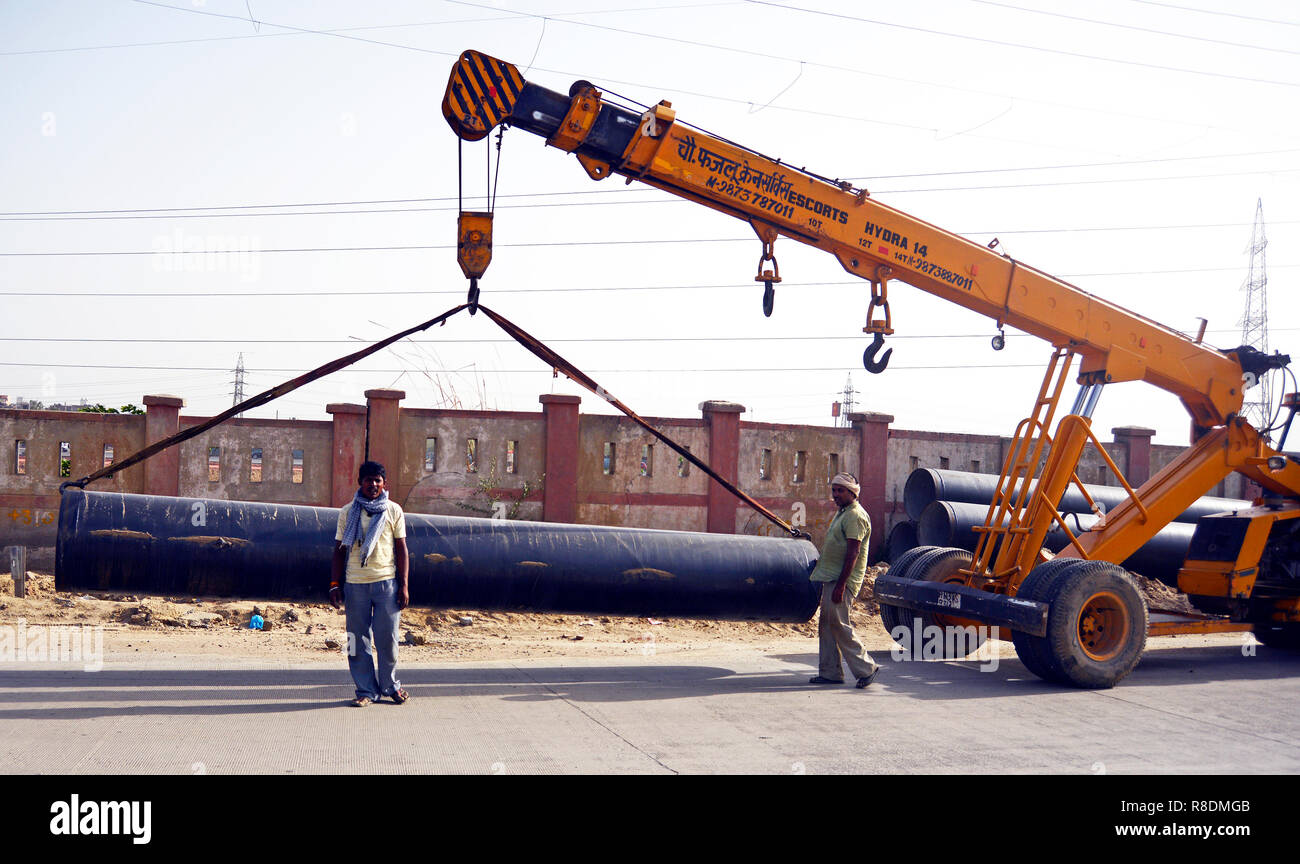Crane holding water pipe and sifting to another place Stock Photo - Alamy