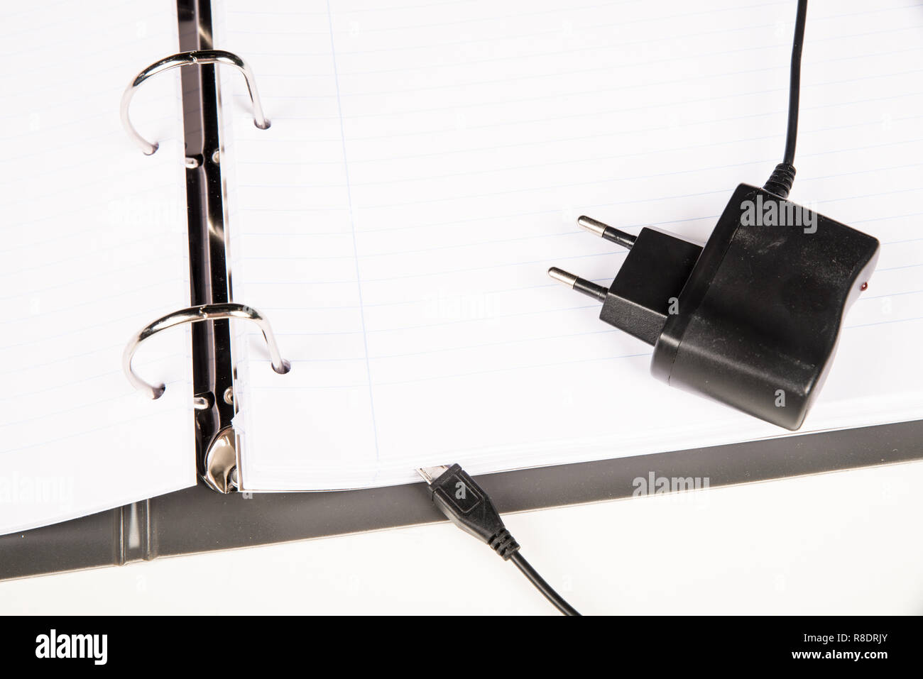 Paper notebook connected to a usb charger, a concept of analog vs ...