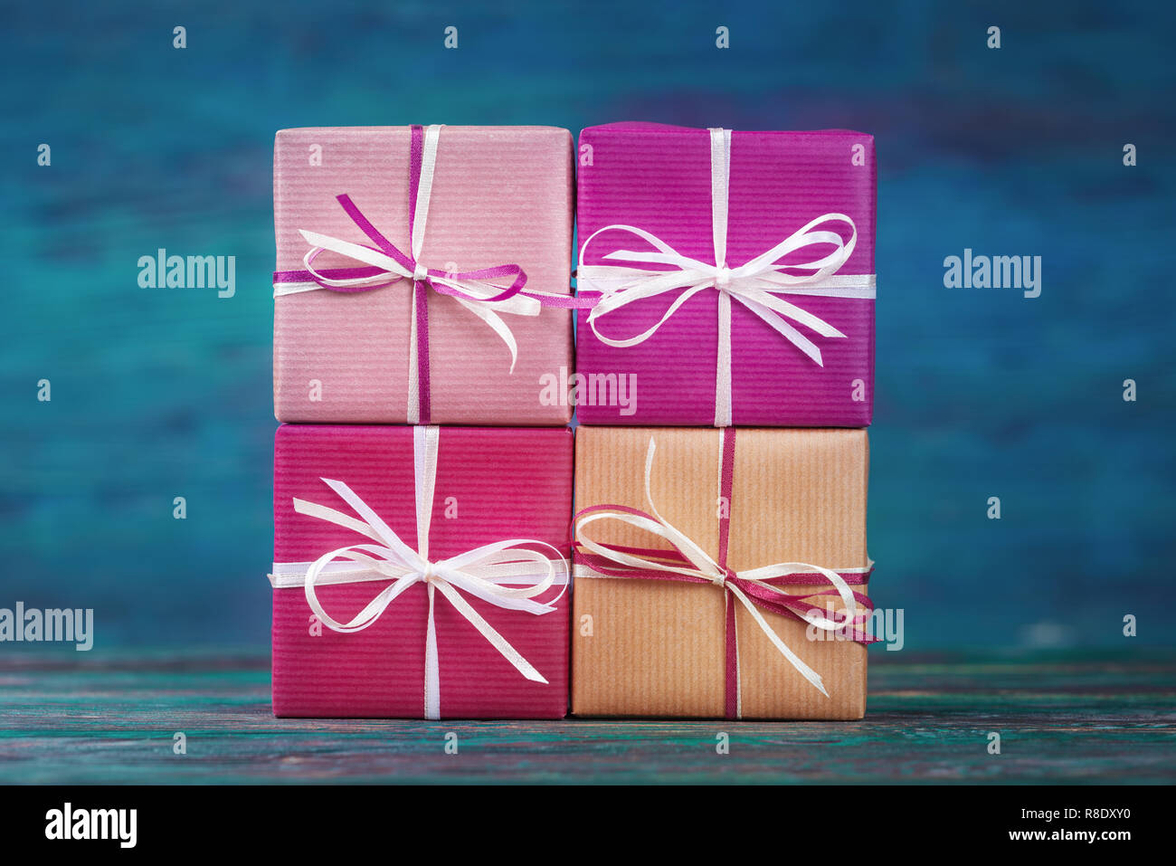 Four gift boxes over blur wooden background Stock Photo - Alamy