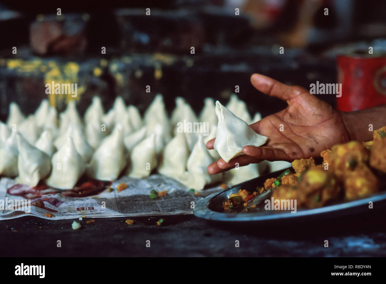A male hand holding a samosa ready for cooking, traditional street food ...